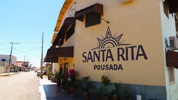 Um edifício com uma placa indicando 'Santa Rita Pousada' e uma fileira de vasos de plantas ao longo da calçada.
