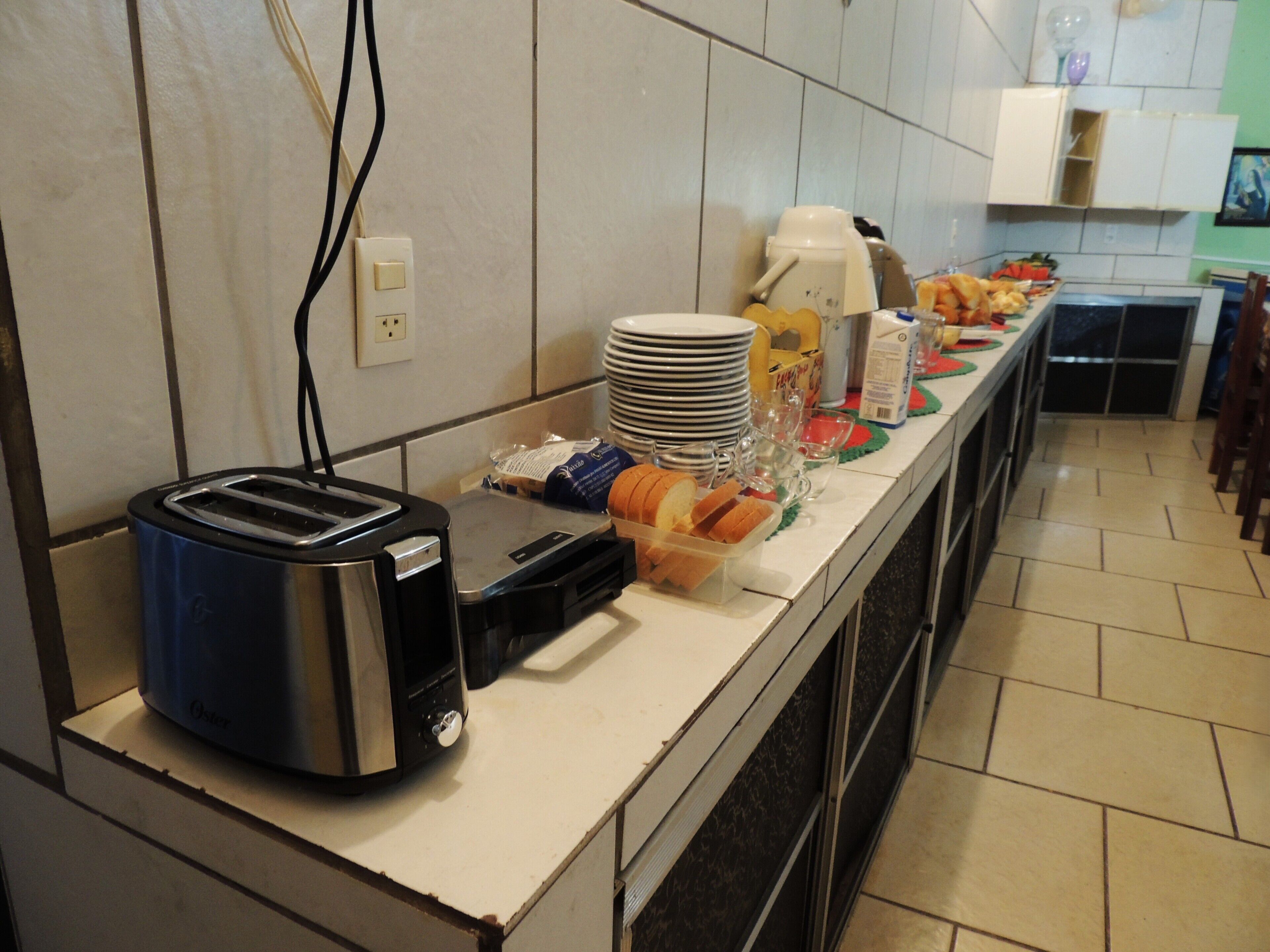Uma bancada de cozinha com uma torradeira, pratos empilhados e uma cafeteira.