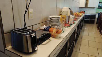 Uma bancada de cozinha com uma torradeira, pratos empilhados e uma cafeteira.