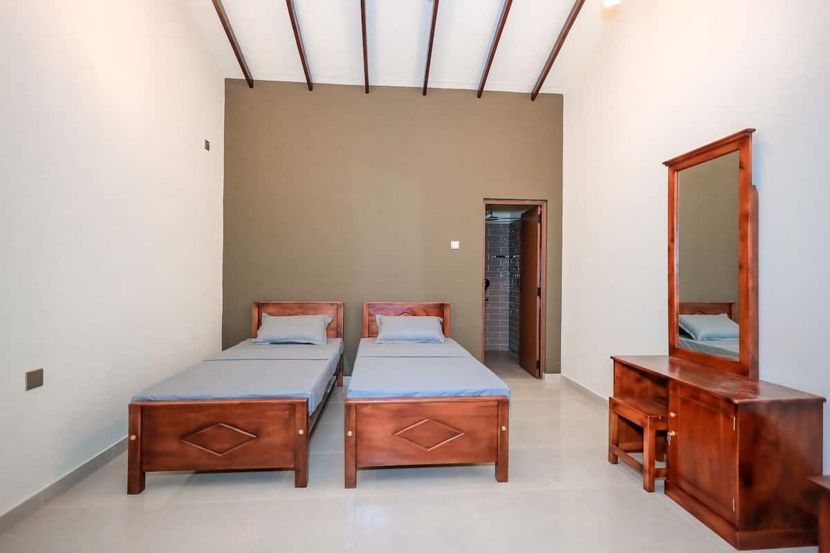 Um quarto com duas camas de madeira, um penteado de madeira e um espelho.