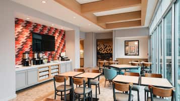 Um café moderno com parede em padrão herringbone, estação de café e mistura de cadeiras de madeira e estofadas.