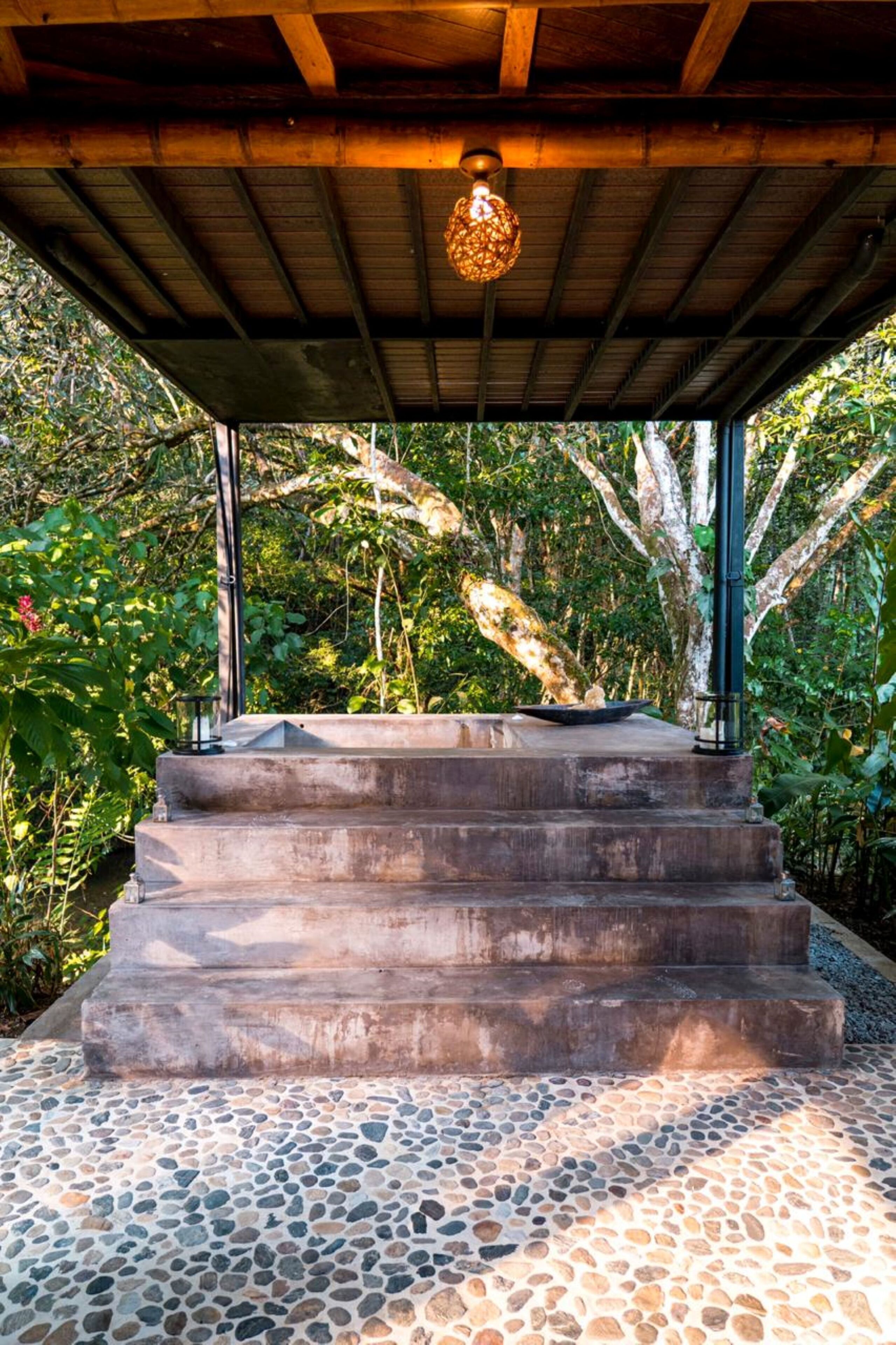 Uma escadaria de pedra leva a uma área coberta com um candeeiro pendurado.