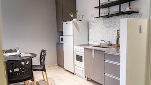 Uma cozinha compacta com área de jantar, incluindo uma mesa com cadeiras, geladeira, forno e micro-ondas.