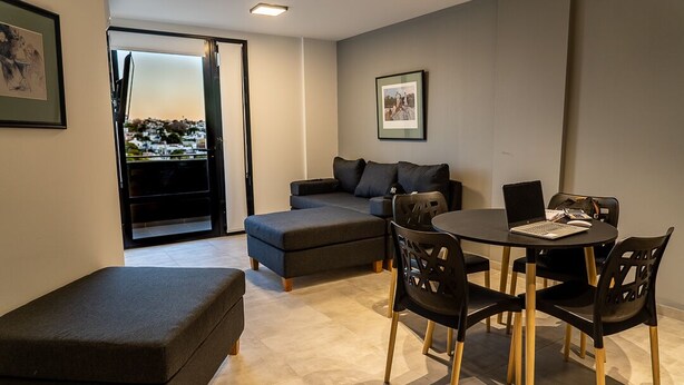 Uma sala de estar moderna com um sofá, um banquinho e uma mesa de jantar com cadeiras.