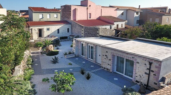 Pátio com um edifício moderno, janelas amplas e fachada de pedra.