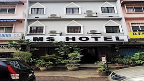 Um hotel com vários andares e uma placa grande com a inscrição 'MS HOTEL'.