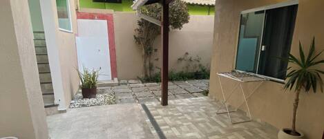Um pátio com piso de azulejos, uma pérgula e um vaso de planta.