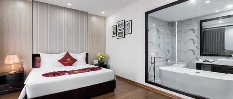 Quarto de hotel moderno com uma cama grande, banheiro separado com banheira e um espelho amplo.