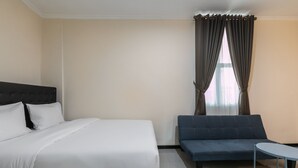 Quarto de hotel com uma cama, um sofá e uma pequena mesa.