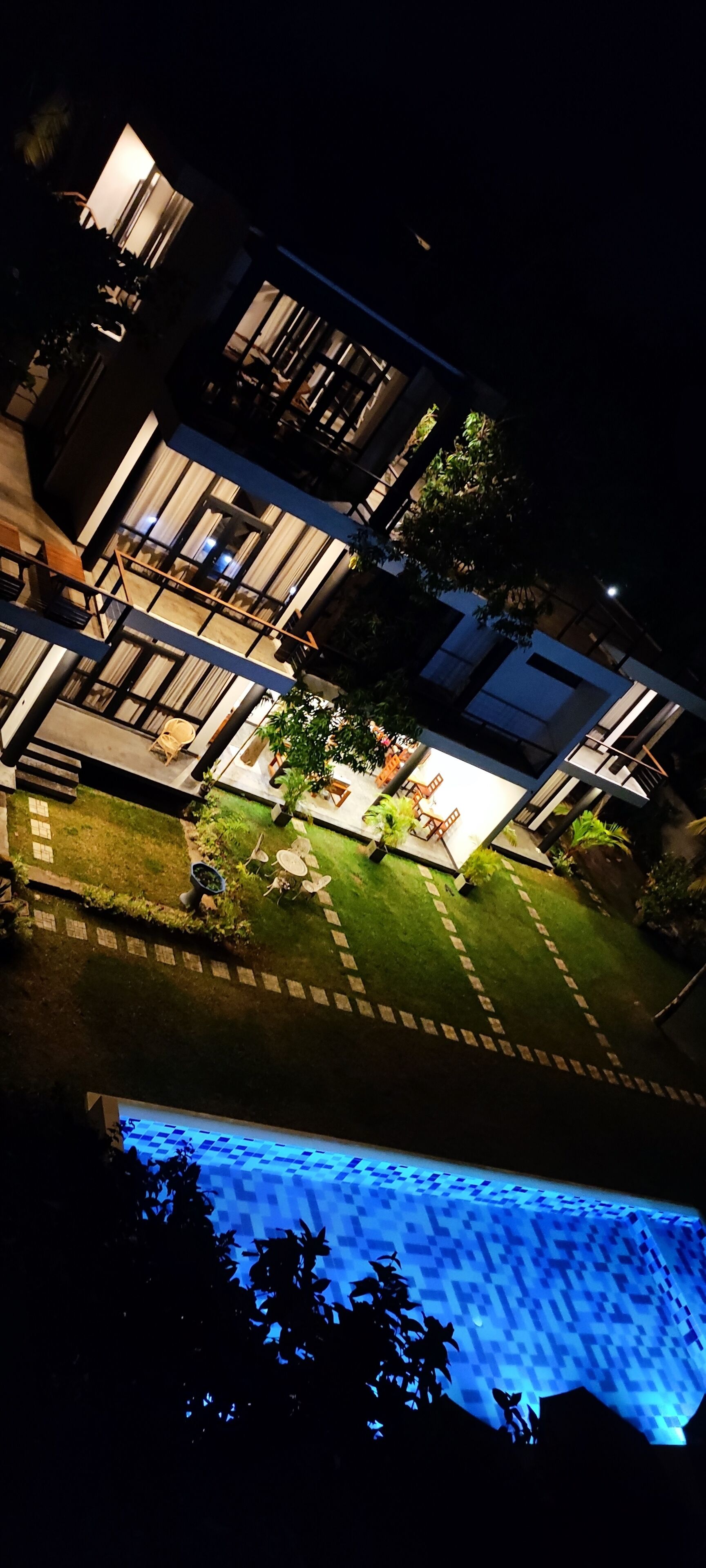 Um edifício moderno com área externa bem iluminada, piscina e um pequeno jardim.