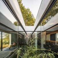 Um interior moderno com teto de vidro, área de estar e plantas dentro de casa.