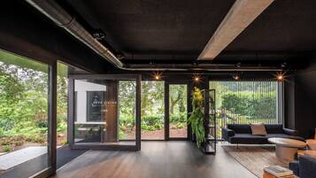 Um interior moderno com grandes portas de vidro que dão para um jardim exuberante, um sofá de cor escura e uma mesa de centro minimalista.