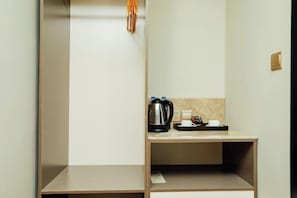 Quarto de hotel com cozinha compacta, incluindo máquina de café, chaleira e bancada.