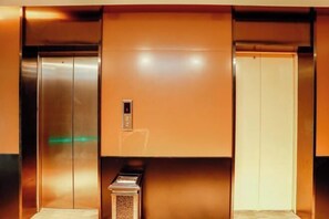 Um elevador com portas metálicas e painel de controle.