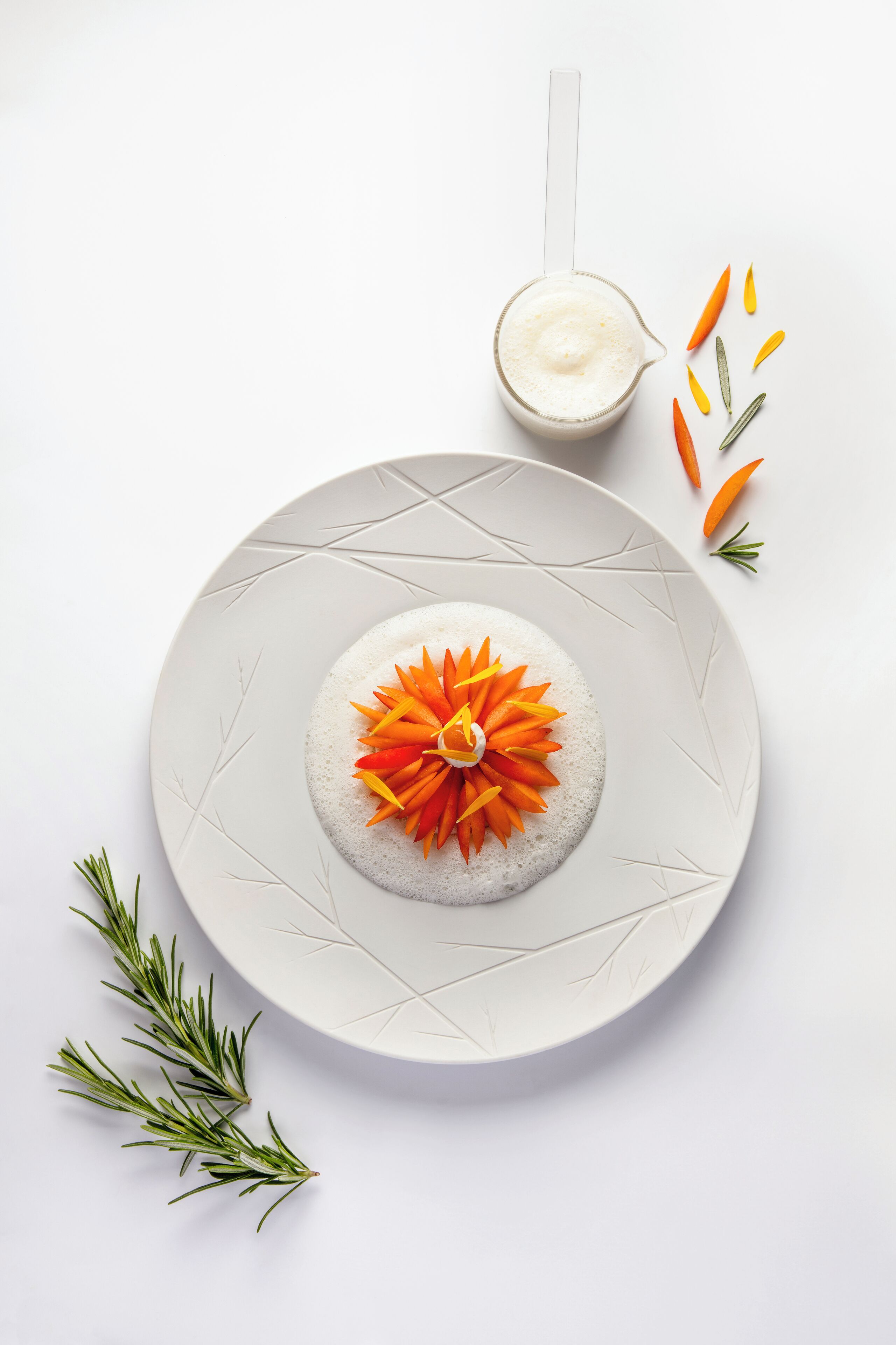 Um prato branco com um alimento esférico no centro, rodeado por uma decoração de cenouras.