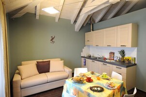 Uma sala de estar aconchegante com um sofá e uma mesa de jantar posta com comida e bebidas.