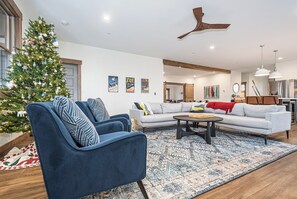 Uma sala de estar moderna com uma grande árvore de Natal, um sofá, uma mesa de centro e um ventilador de teto.