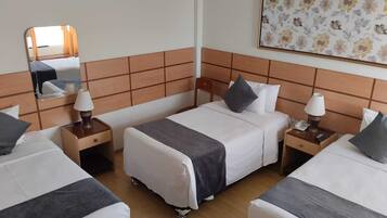 Quarto de hotel com duas camas de solteiro, um espelho grande, uma obra de arte floral na parede e uma cabeceira de madeira.