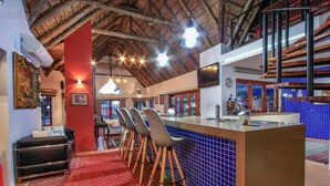 Cozinha ampla com área de bar, paredes vermelhas e teto de colmo.