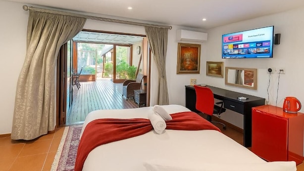 Quarto de hotel com cama, escrivaninha, televisão e vista para o exterior.
