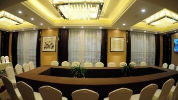 Uma sala de conferências com uma mesa redonda, cadeiras brancas e um lustre.
