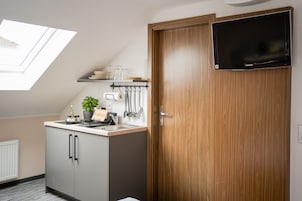 Uma cozinha moderna com claraboia, televisão integrada e porta de madeira.