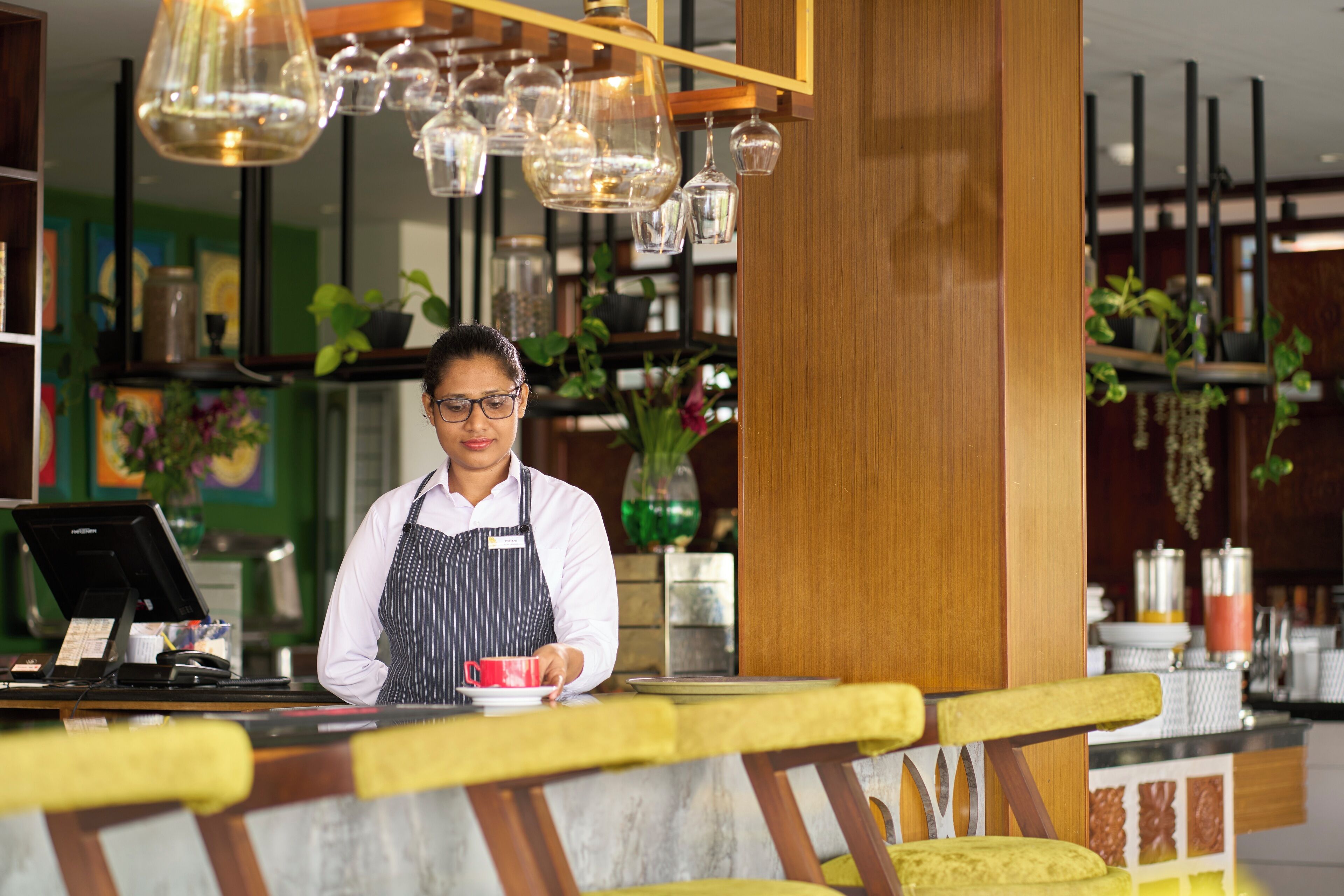 Uma área de recepção de hotel com um balcão de madeira, uma máquina registradora e uma cafeteira.
