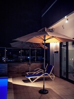 Uma área à beira da piscina com espreguiçadeiras e guarda-sóis.