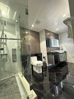 Uma casa de banho moderna com cabine de duche em vidro, sanita e lavatório com espelho.