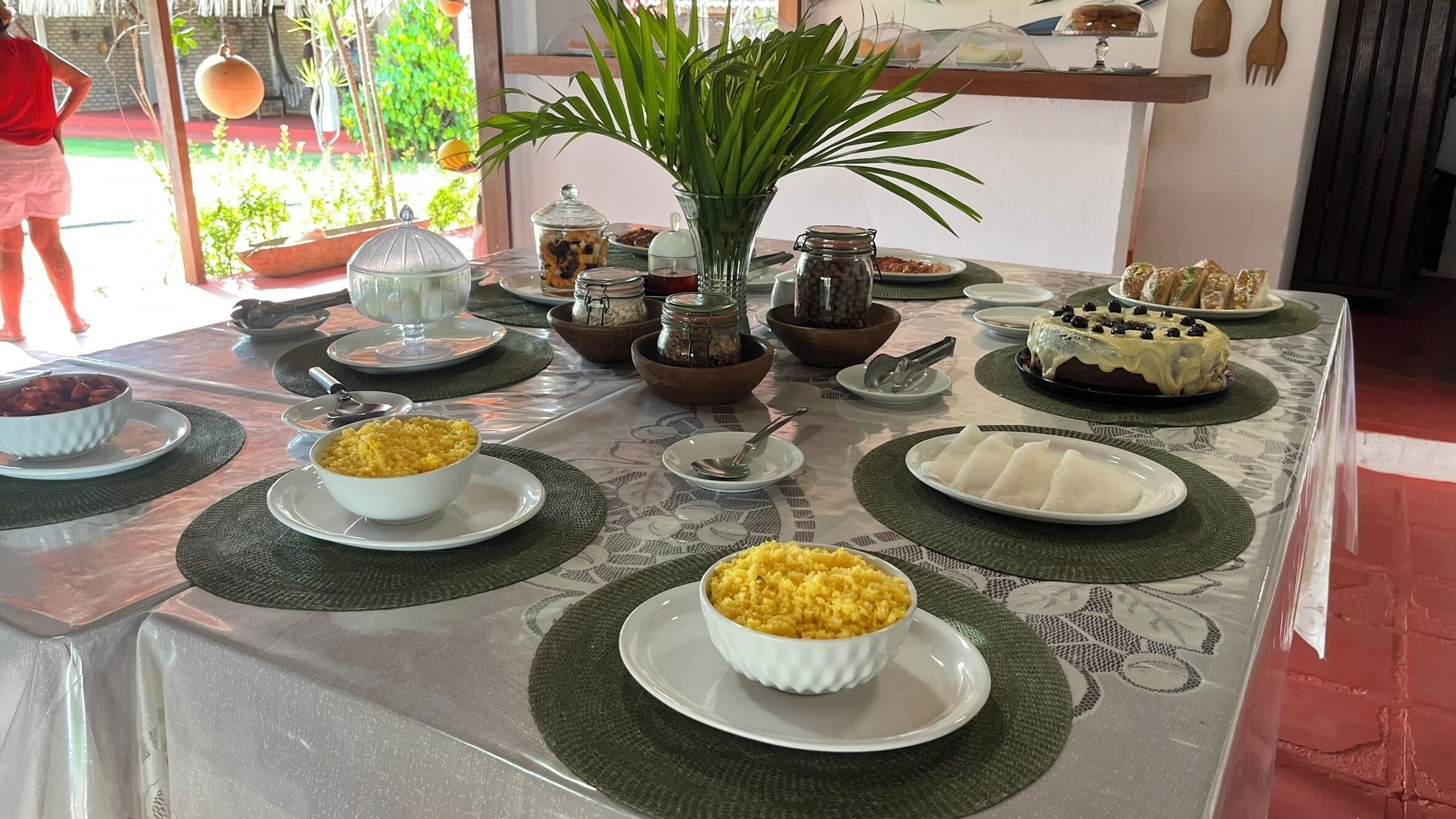 Uma mesa de jantar com diversos pratos, incluindo tigelas de comida, um bolo e uma planta em vaso.