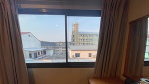 Quarto com uma grande janela com vista para um edifício com torre do relógio.