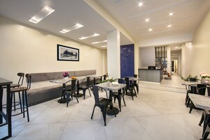 Uma sala de jantar moderna com várias mesas e cadeiras, um sofá e uma escada que leva a um andar superior.