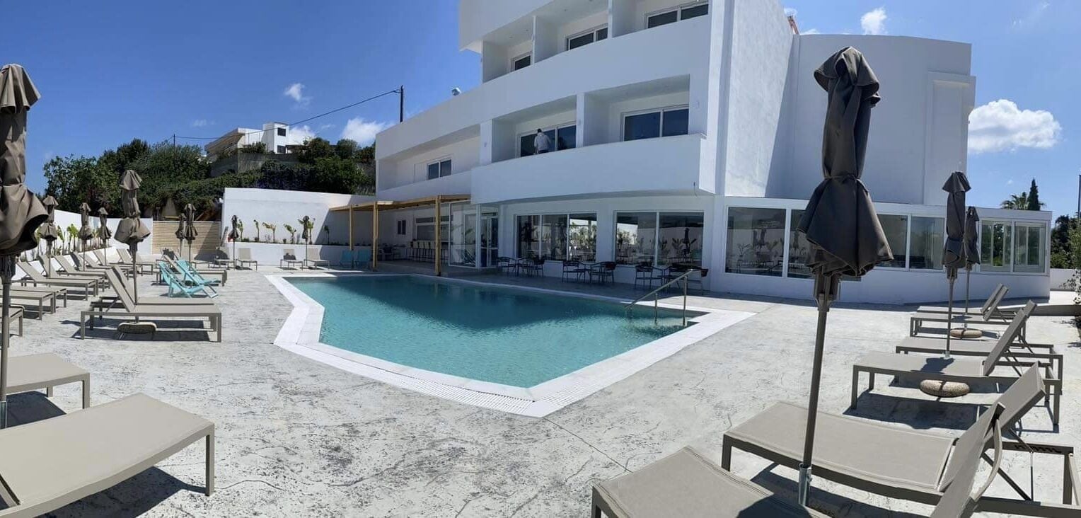 Um edifício moderno com área de piscina, cadeiras de lounge e guarda-sóis.
