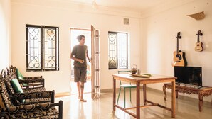 Quarto com sofá, mesa, televisão e guitarras na parede.