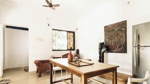 Uma sala de jantar com mesa de madeira, cadeiras, um vaso e um objeto decorativo na parede.