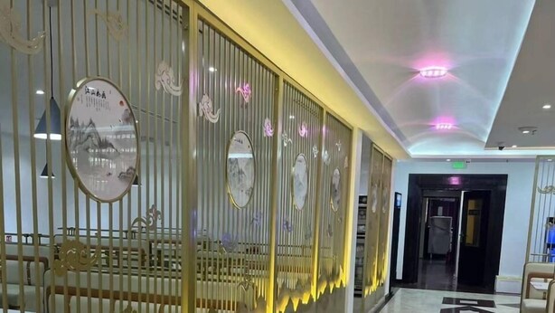 Corredor de hotel com decoração na parede, incluindo arte tradicional e luminária moderna.