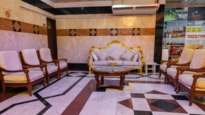 Um hall com piso estampado, uma mesa redonda central e quatro cadeiras estofadas.