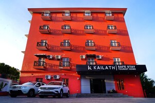 Um edifício vermelho com várias varandas e um letreiro que diz 'KAILATH Safe Stay Tourist Home'.