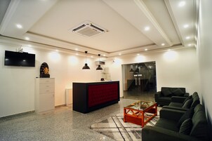 Uma sala de estar moderna com uma parede de destaque vermelha, um sofá preto, uma mesa de centro de vidro e uma televisão de tela plana fixada na parede.