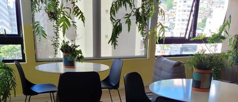 Uma sala de reuniões moderna com uma mesa redonda, cadeiras pretas e plantas em vasos.