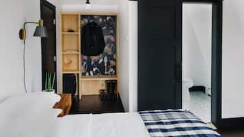 Quarto com cama, guarda-roupa, escrivaninha e banheiro.