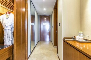 Corredor de hotel com painéis de madeira, um balcão de recepção com comodidades e um roupão pendurado em um suporte.