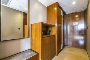 Um corredor com um armário de madeira, um espelho e uma porta.