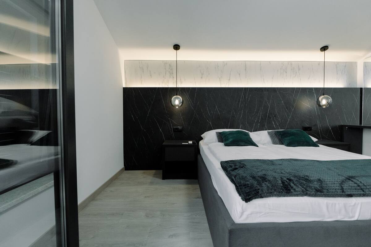 Quarto moderno com cama, mesas de cabeceira e um espelho grande.