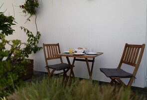 Uma pequena mesa de madeira com duas cadeiras, um copo de suco e um prato de comida.