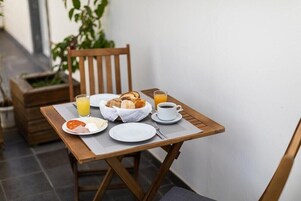 Disposição para o café da manhã com croissants, suco de laranja, café e um prato de comida sobre uma mesa de madeira.