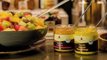 Uma tigela de salada de frutas e dois potes de condimentos veganos e orgânicos.