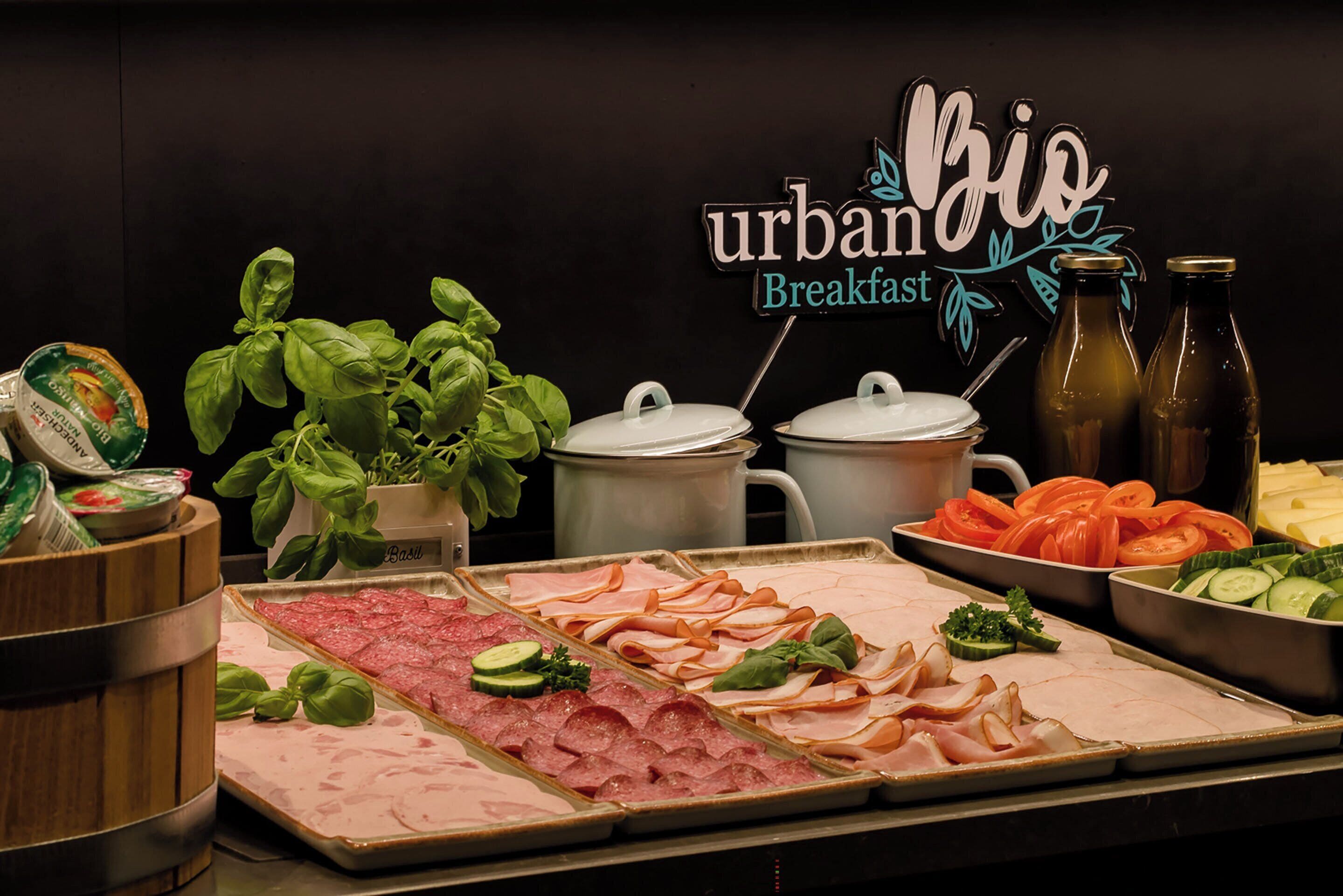Um buffet de café da manhã com diversos tipos de carne, vegetais e uma placa com a inscrição 'urban breakfast'.