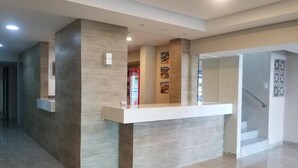 Uma área de recepção com balcão, refrigerador de Coca-Cola e escada.