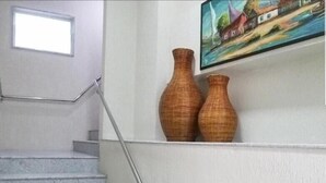 Uma escada com guarda-corpos de metal, uma janela e dois vasos de vime na parede.